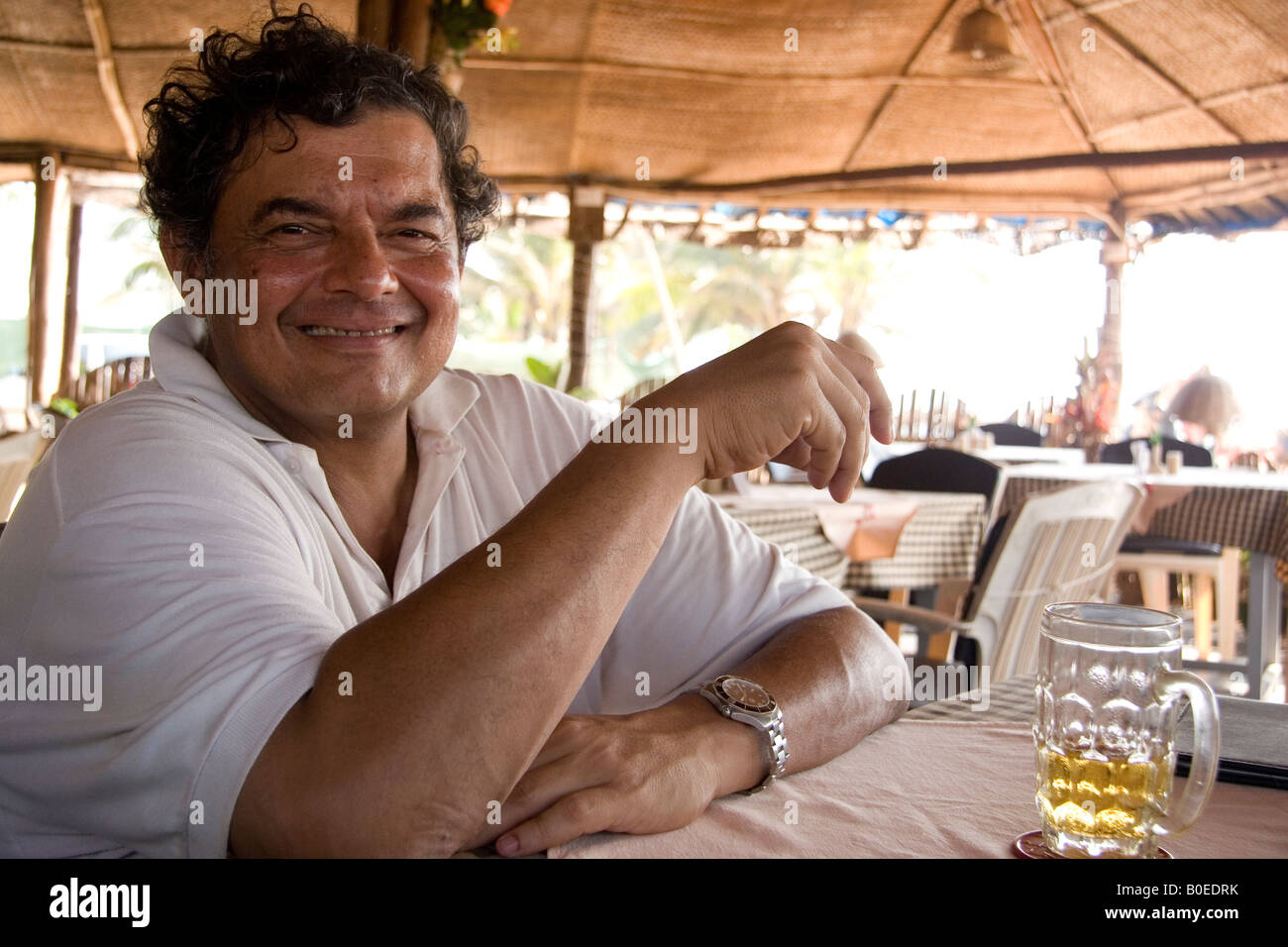 A man enjoys a beer in a beach shack on Bogmalo Beach in Goa, India ...
