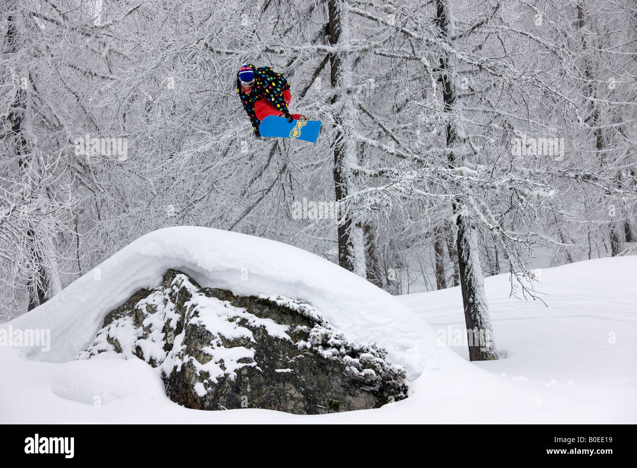 Snowboarder jumps from a rock off piste Stock Photo - Alamy