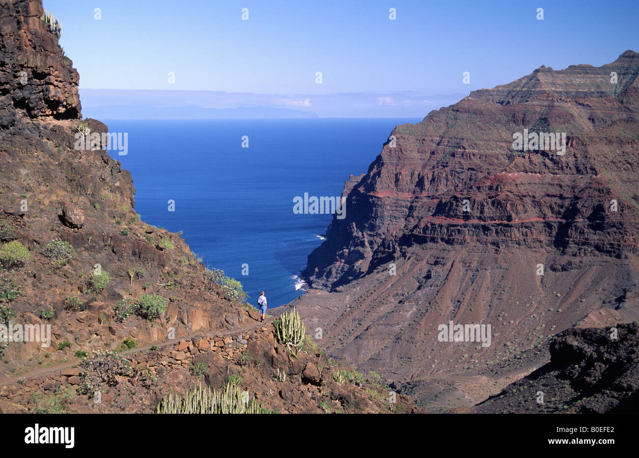 A walker on the mountain path to Playa de Guigui, Gran Canaria, Canary ...
