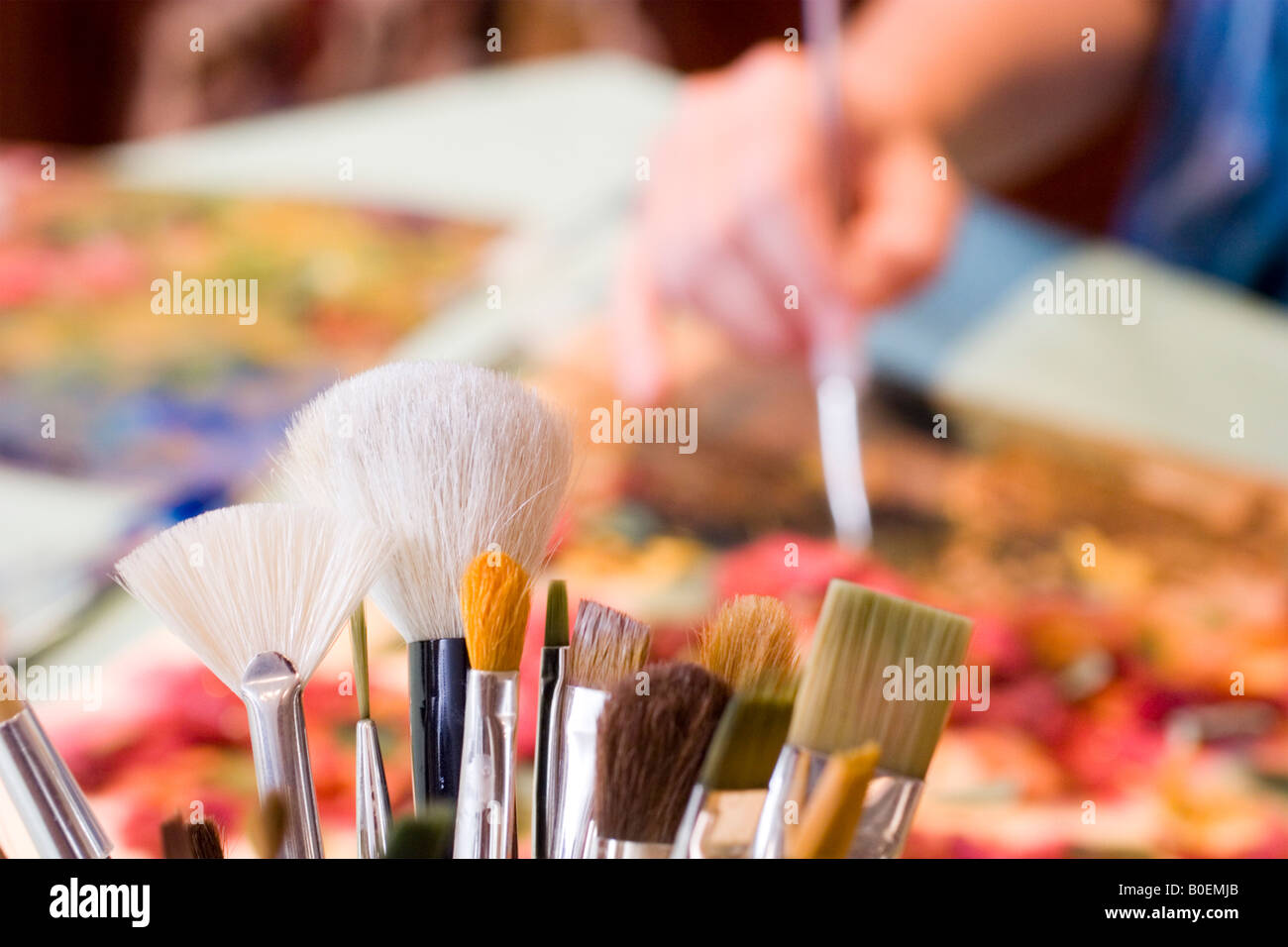 A closeup of an artist hand at work on a new painting with brushes at ...
