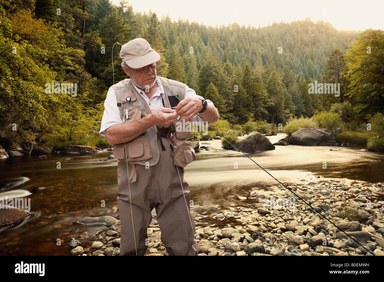 Man in his Sixties tying fly while Fly Fishing along river in Northern ...