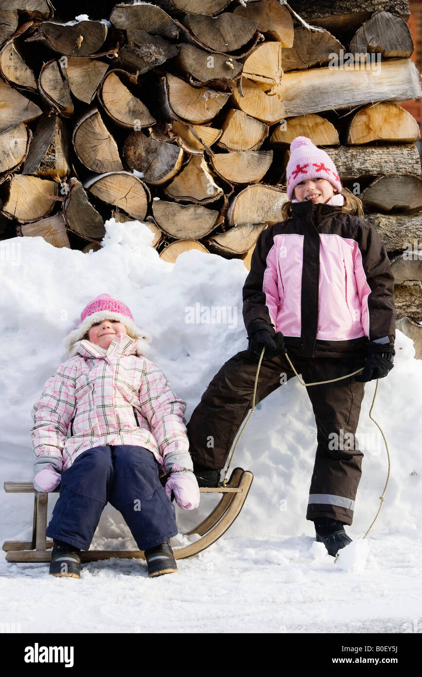 Young girls posing with sledge on snow Stock Photo - Alamy