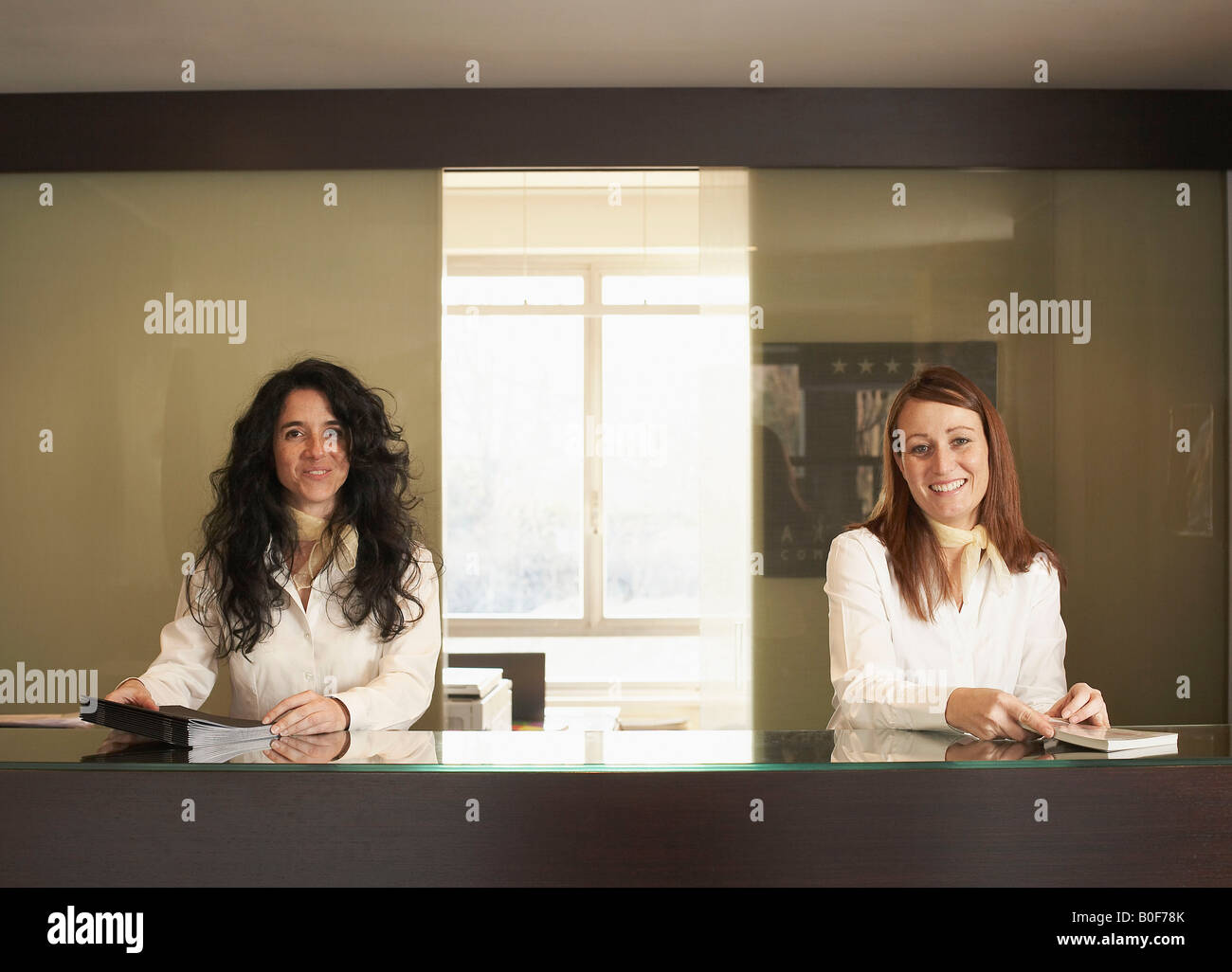 Two Receptionists behind hotel counter Stock Photo - Alamy