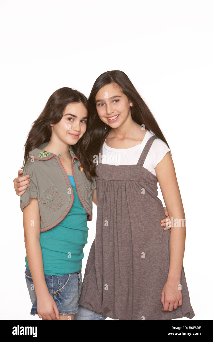 two sisters hug each other as they smile against a white background ...