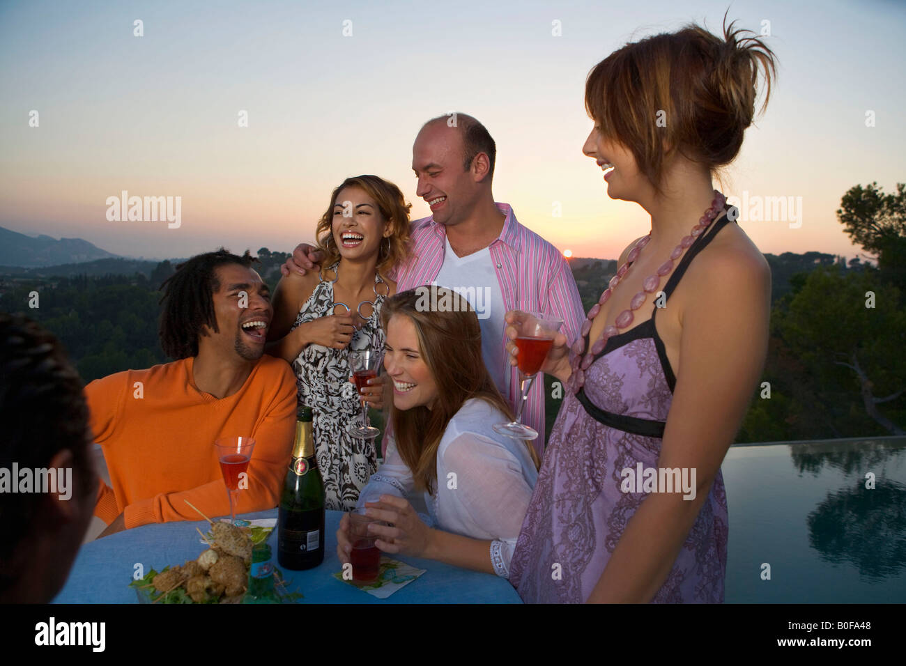 Men and woman at a party at sunset Stock Photo - Alamy