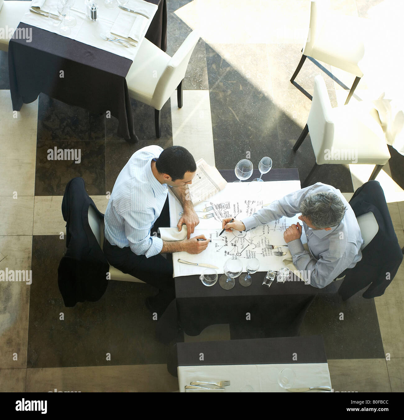 Two businessmen writing on tablecloth Stock Photo - Alamy