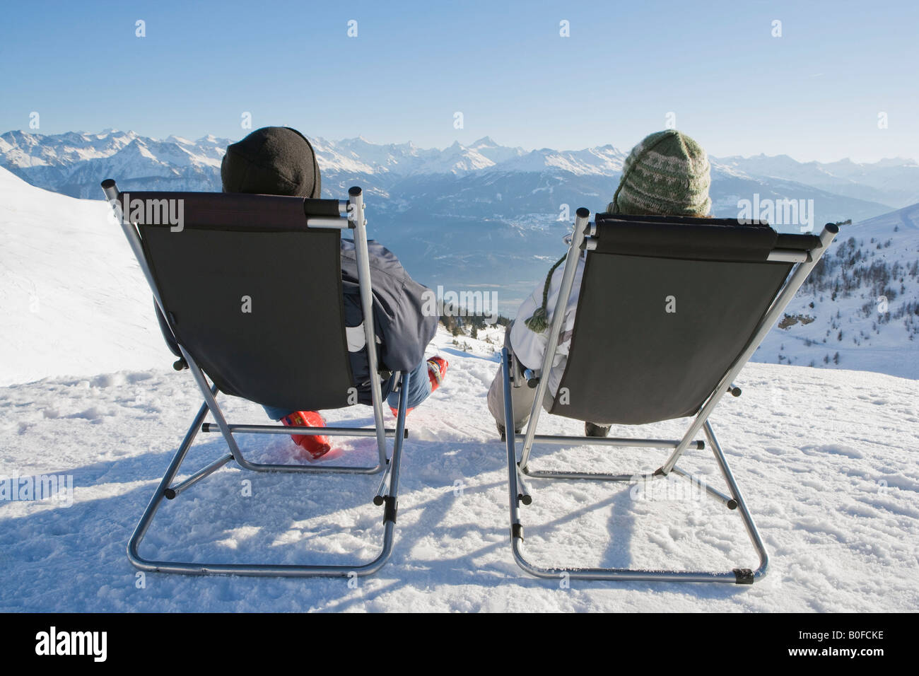 Man, woman relax on deck chairs in snow Stock Photo - Alamy