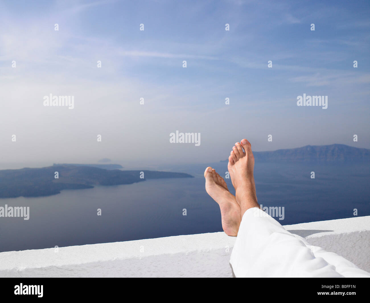 Men's feet on a low wall, sea view Stock Photo - Alamy