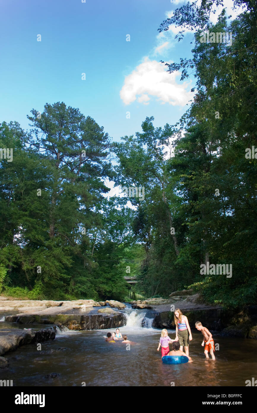 Children playing in water below waterfall under clouds Stock Photo - Alamy