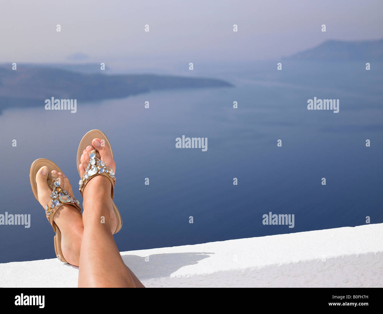Woman's feet on a low wall, sea view Stock Photo - Alamy