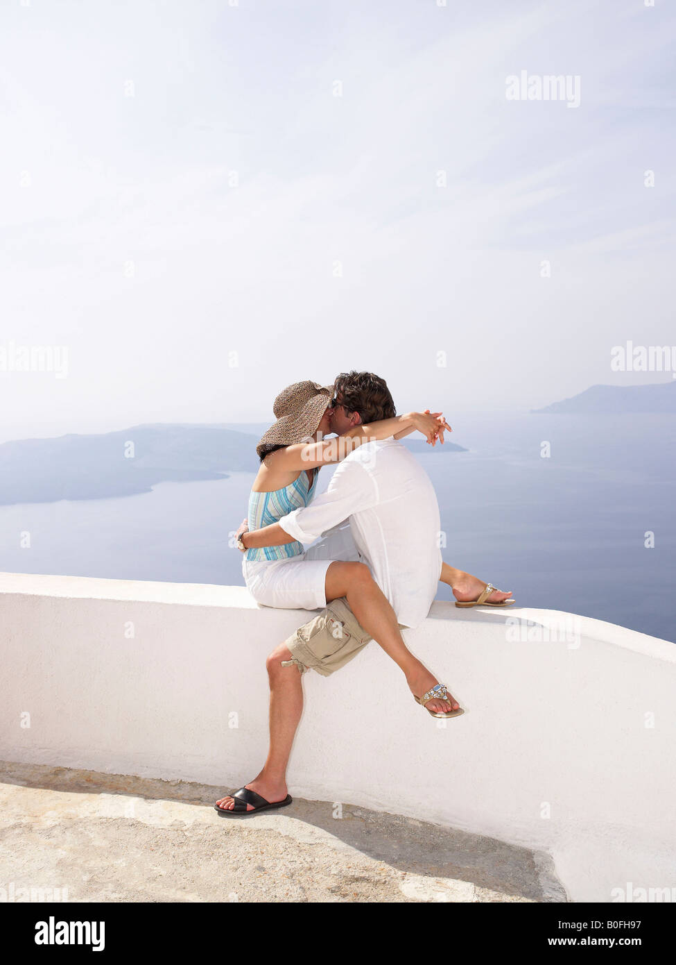 Couple kissing on a low wall, sea view Stock Photo - Alamy