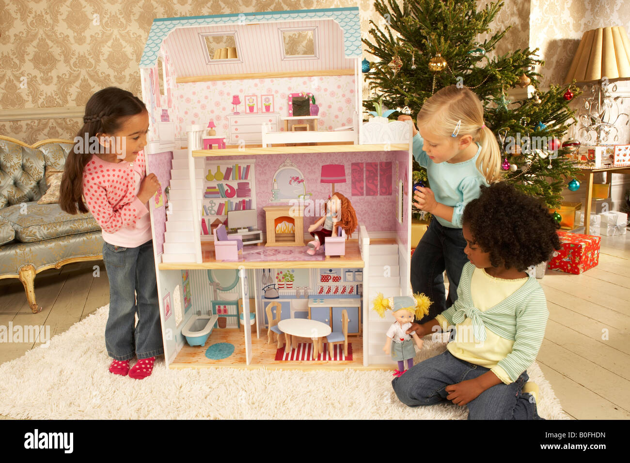 three girls gather at a Christmas tree at Christmas time and play with ...