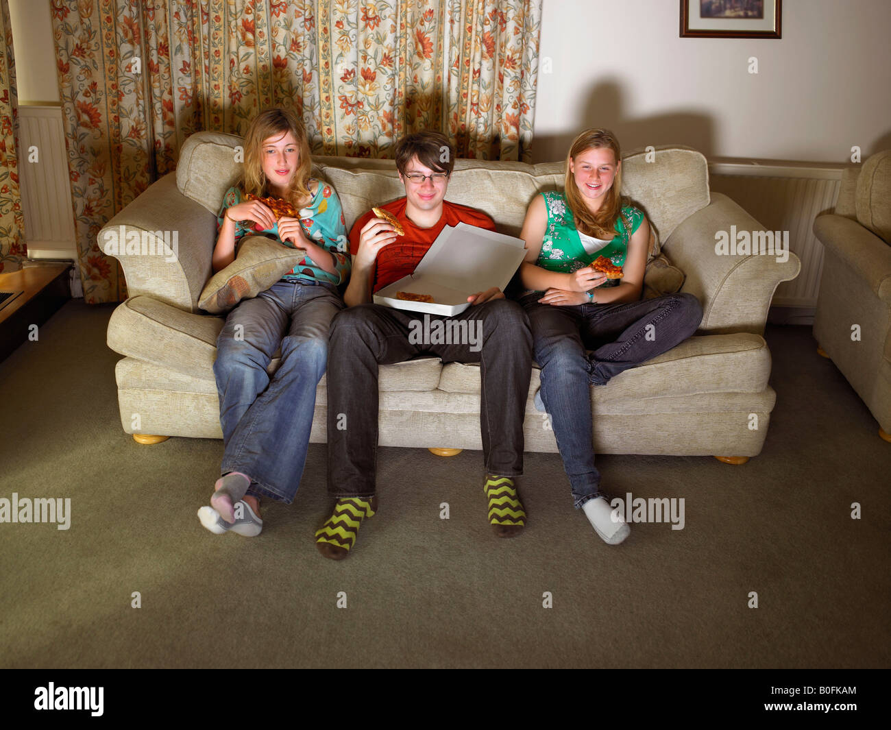 Females and male on sofa, eating pizza Stock Photo - Alamy