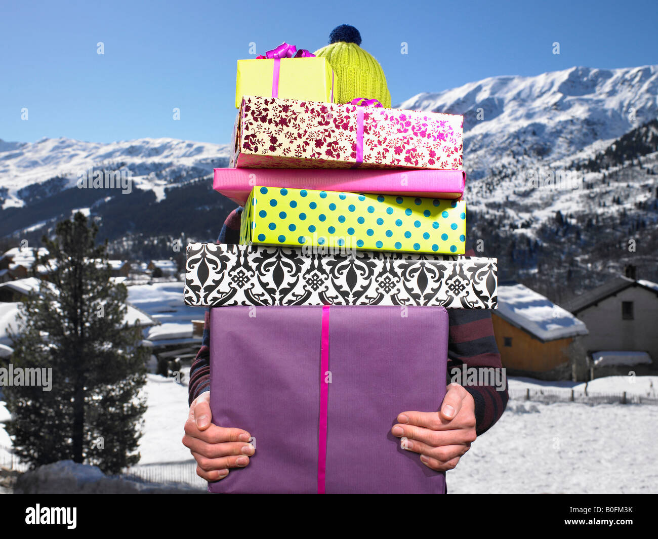 Young man holding pile of presents Stock Photo - Alamy