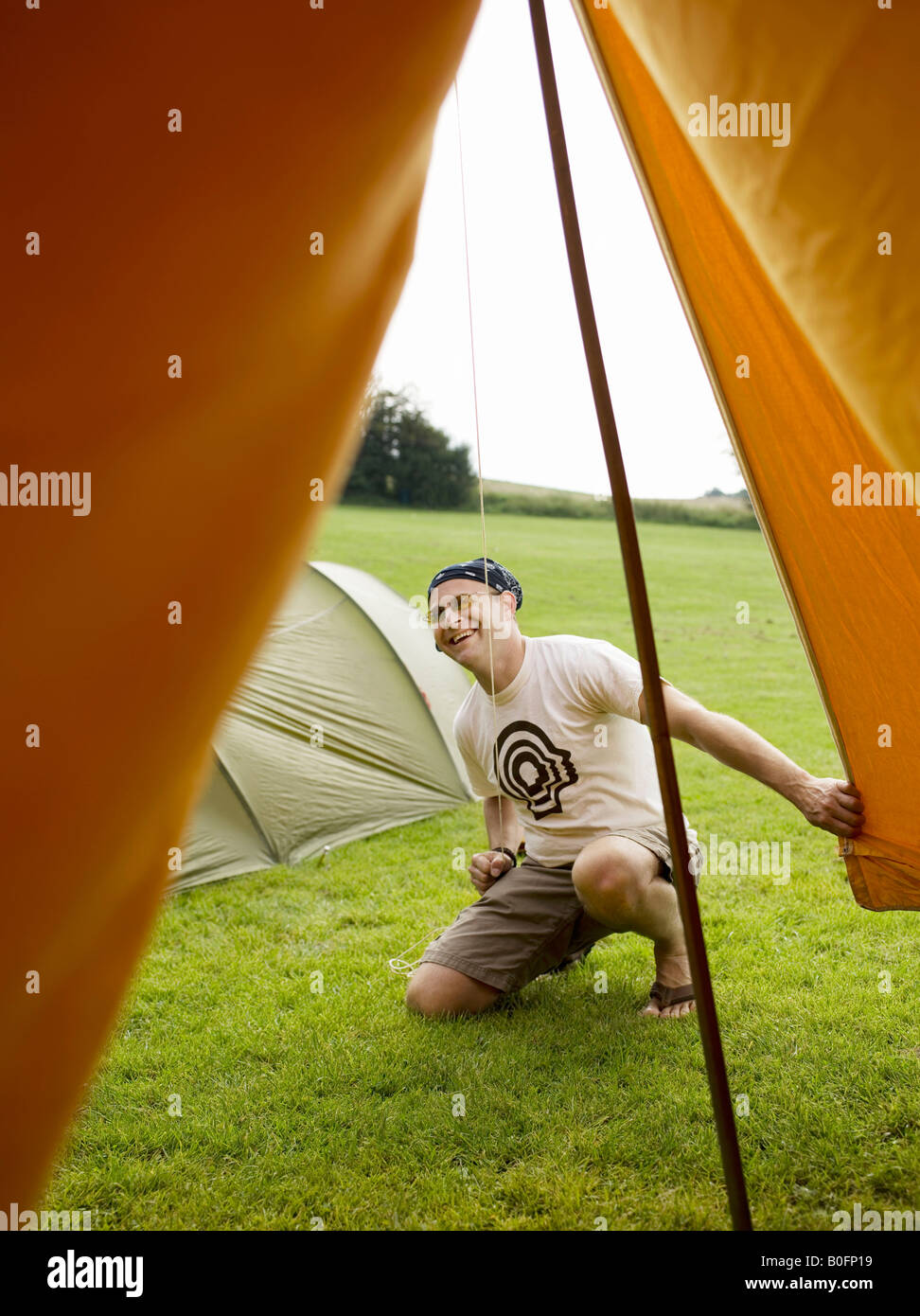 Man setting up a tent and laughing Stock Photo - Alamy