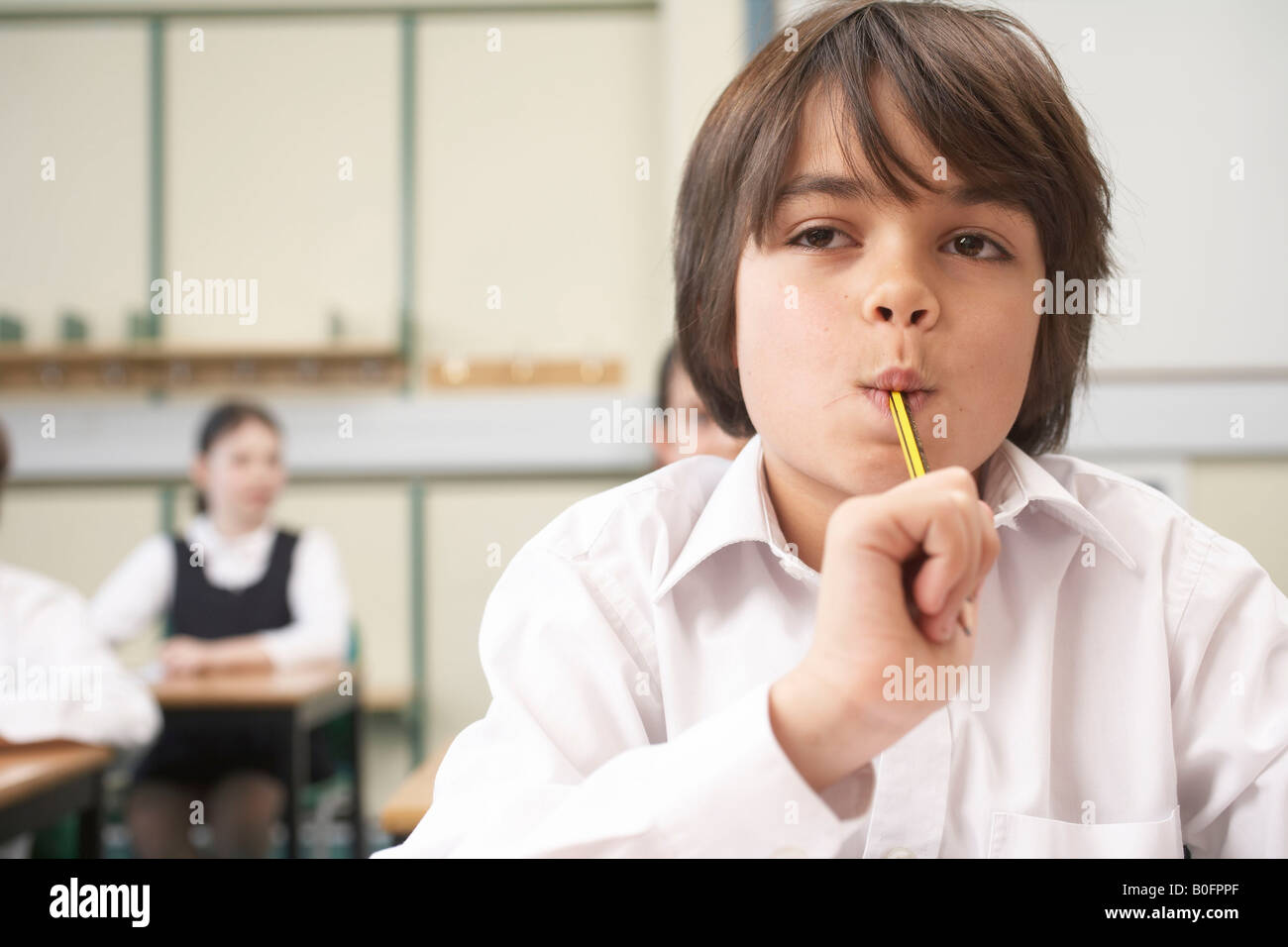 Boy with pencil in mouth, in classroom Stock Photo - Alamy