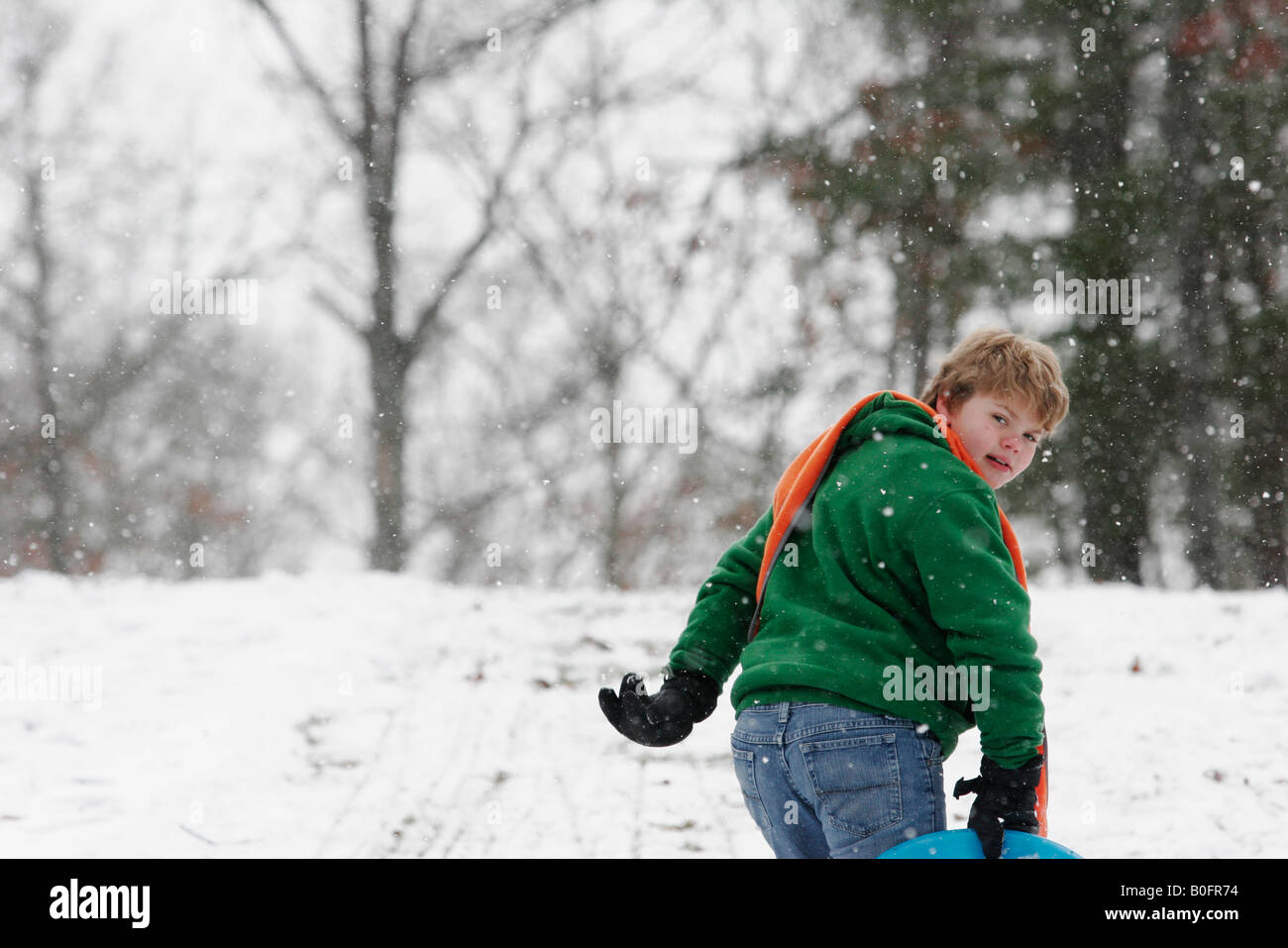 Young boy pulling a sledding up hill in the falling snow Stock Photo ...
