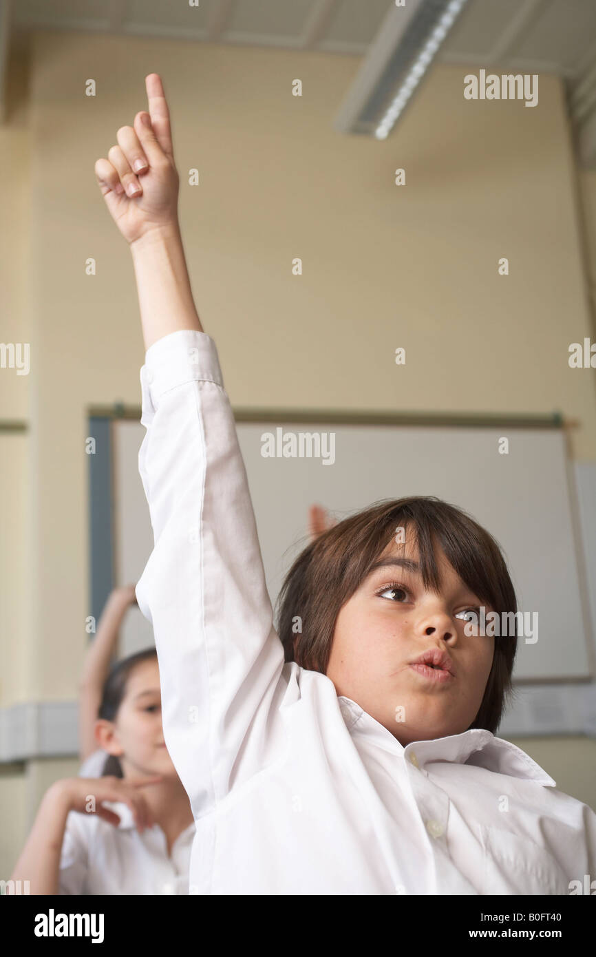 Boy raising his hand in classroom Stock Photo - Alamy