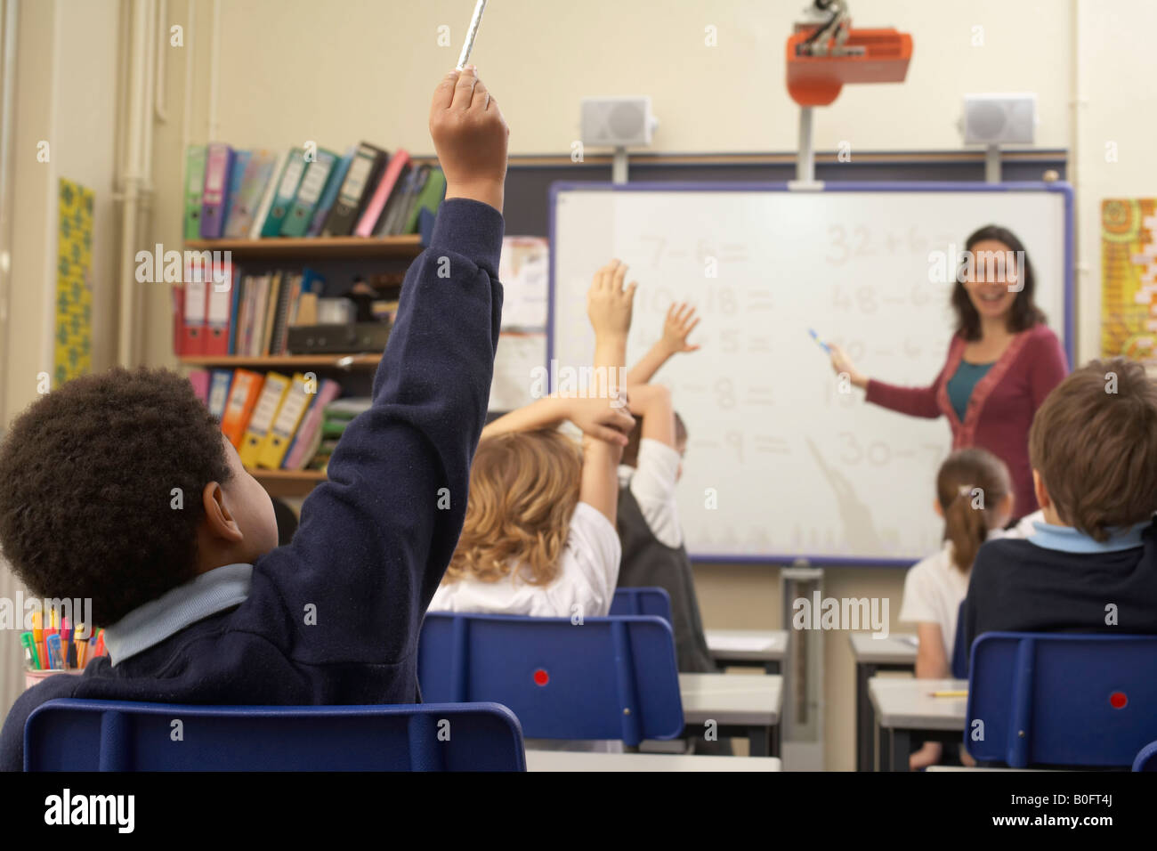 Children raising hands in classroom Stock Photo - Alamy