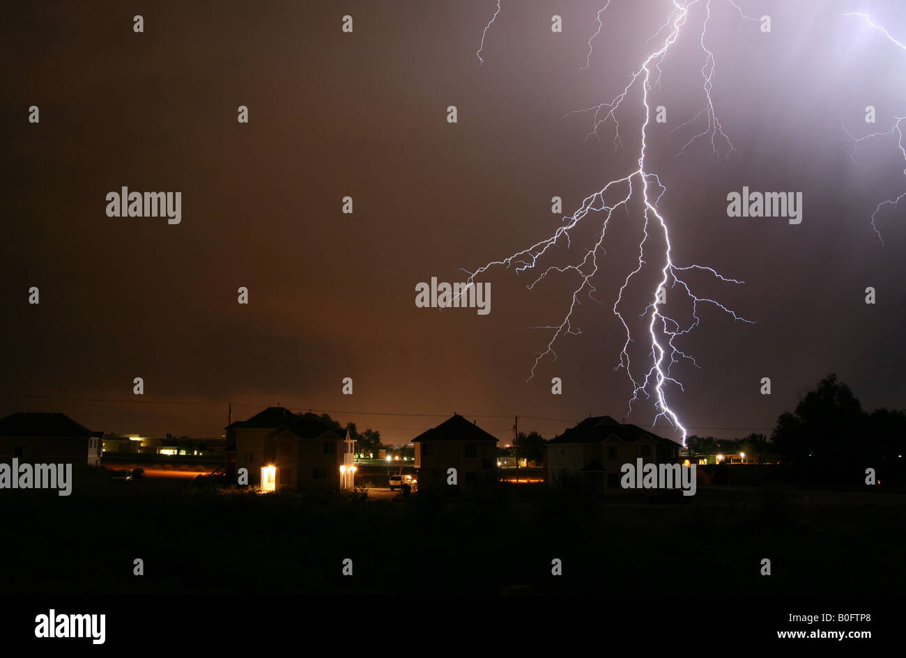 lightning striking near houses in a city at night Stock Photo - Alamy