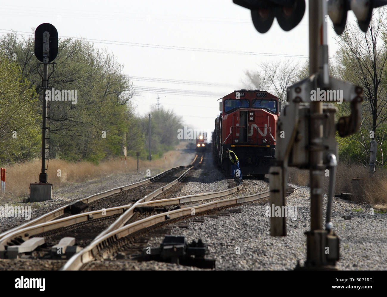 A railroad man looks around a train on a rail siding as a second train ...