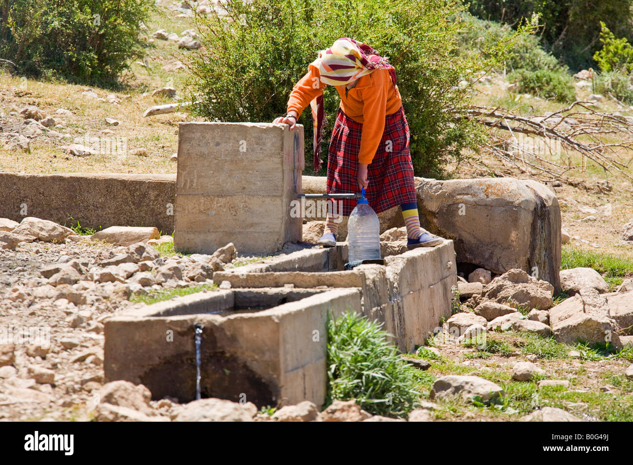 Young girl collecting water from a mountain water source Stock Photo ...