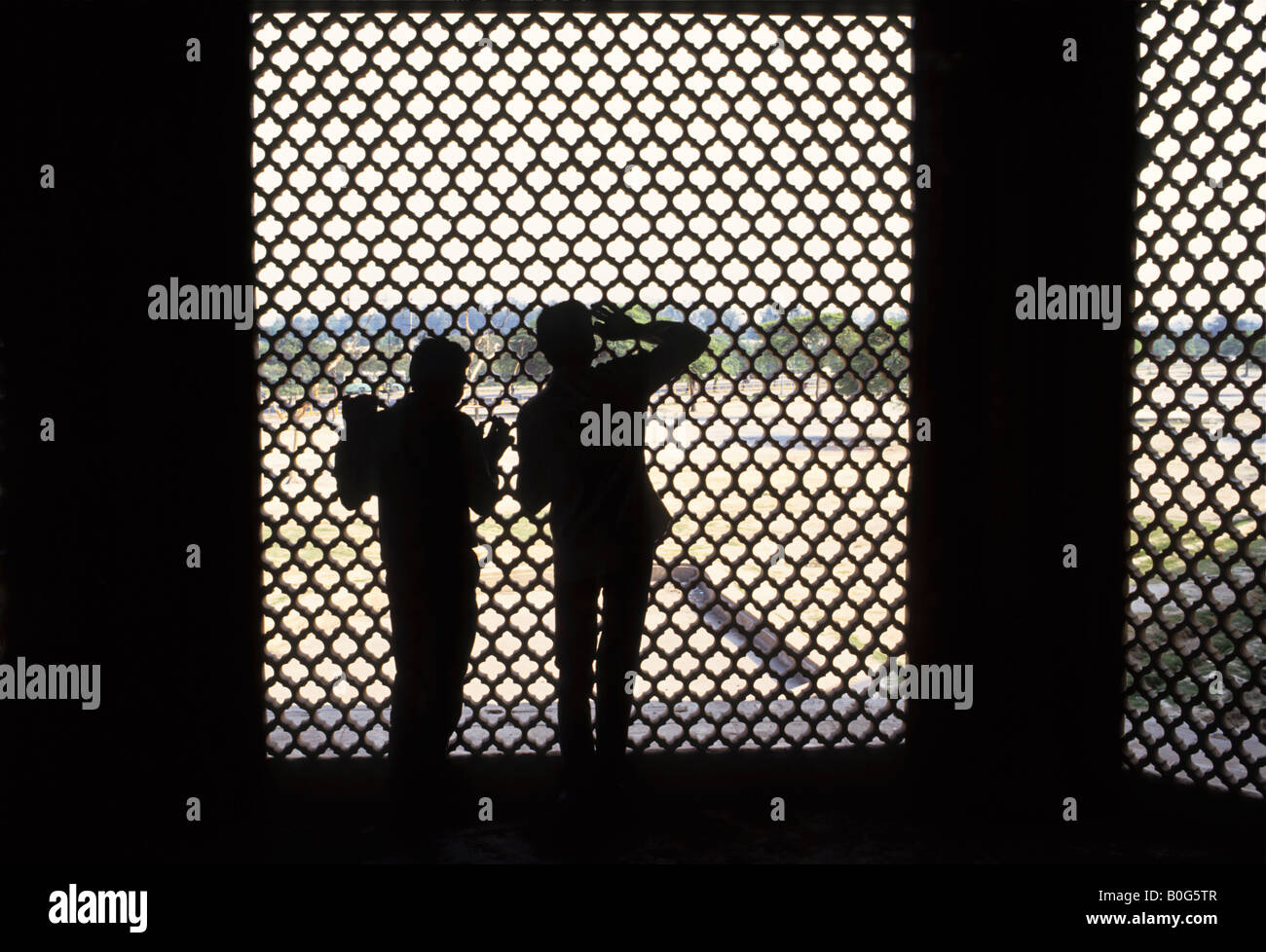 Two visitors looking through a window frame at the Red Fort, Agra IN ...