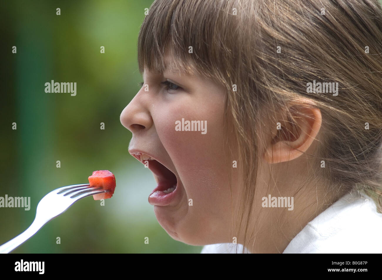 Young girl eating strawberry Stock Photo - Alamy