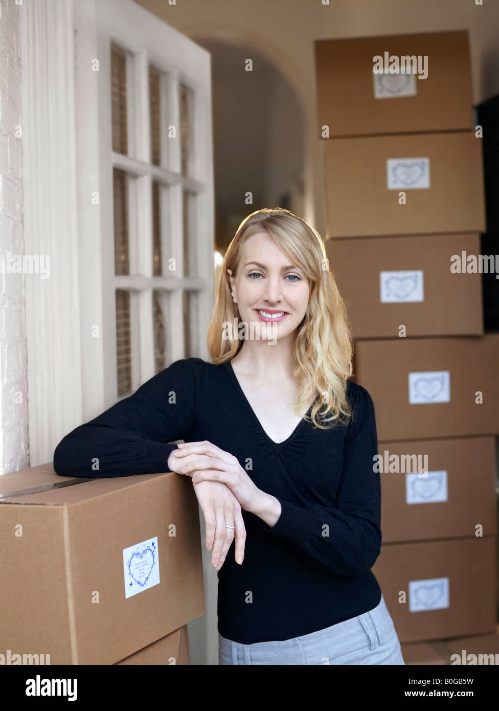 Woman leaning on boxes in doorway Stock Photo - Alamy