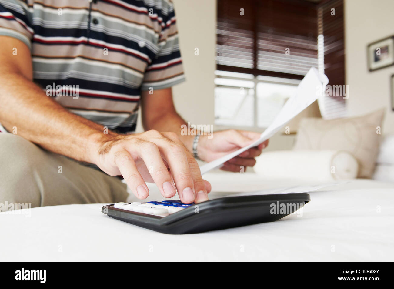 Male's hand adds up bills on calculator Stock Photo - Alamy