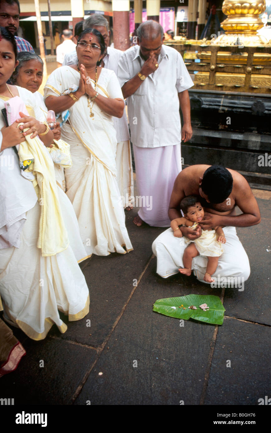 A father feeding his baby during a blessing ceremony in a Hindu temple ...