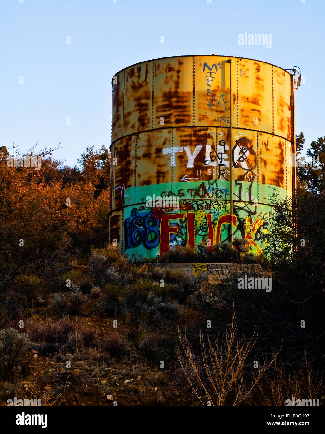 An old rusty water tank covered with graffiti sits in the setting sun ...