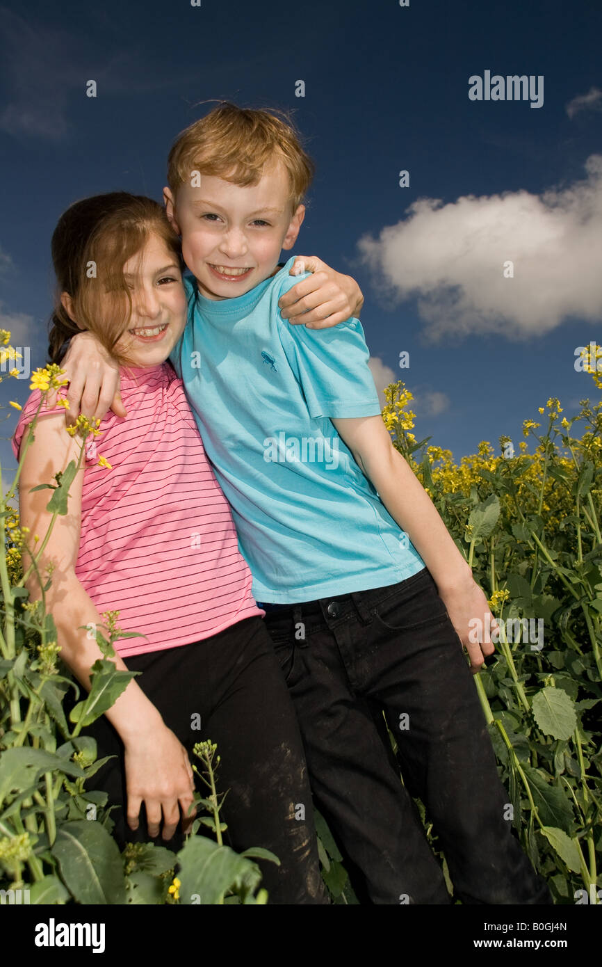 young boy and girl cuddling in yellow field with blue sky Stock Photo ...