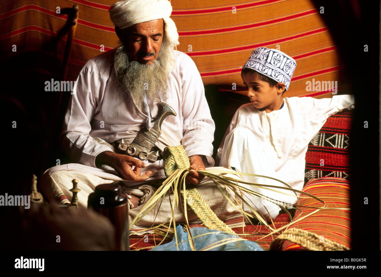 A man teaching a child how to weave a basket, Oman Stock Photo - Alamy