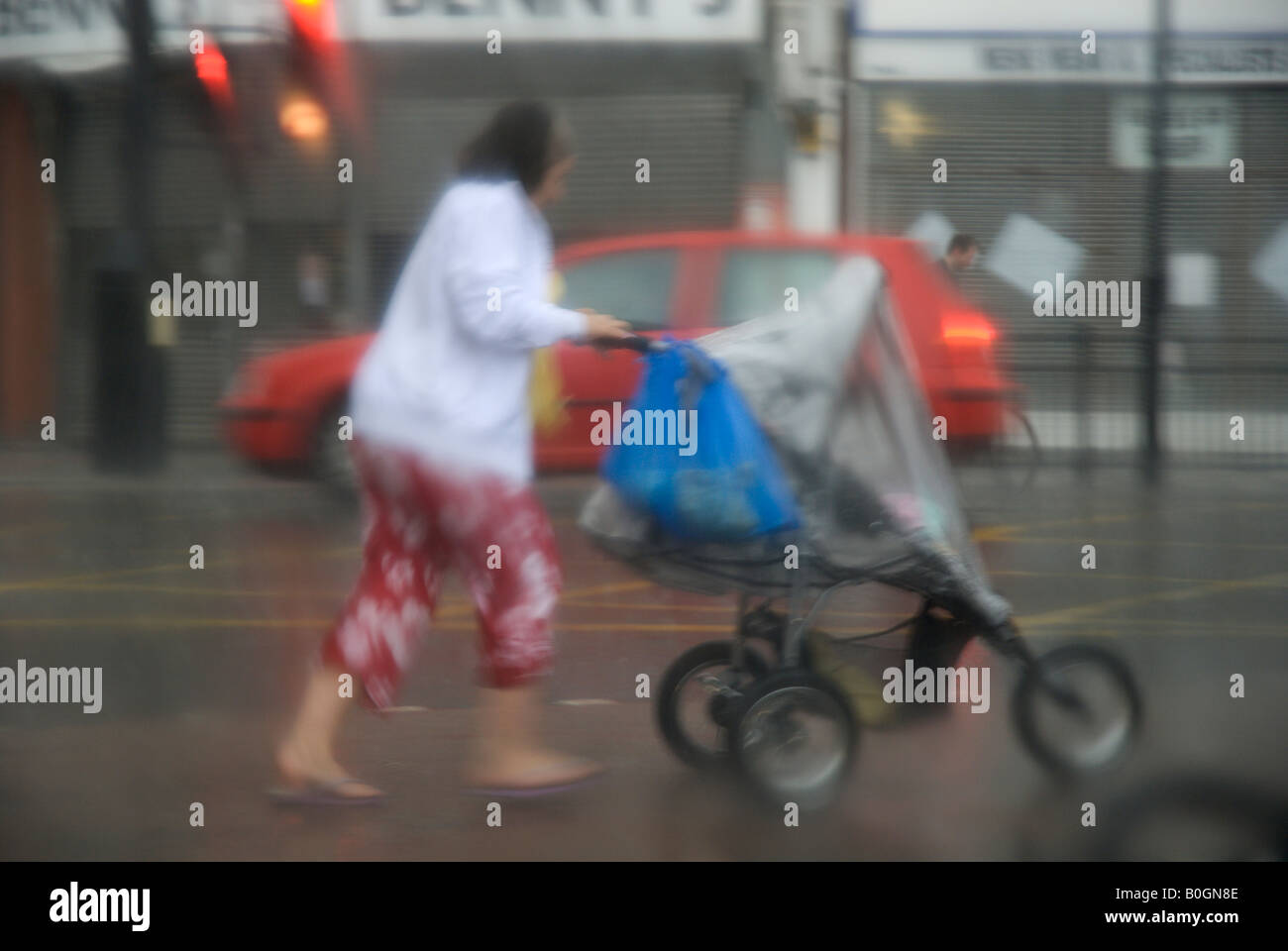 Woman pushing buggy across the road in a thunder storm,Hackney Stock ...