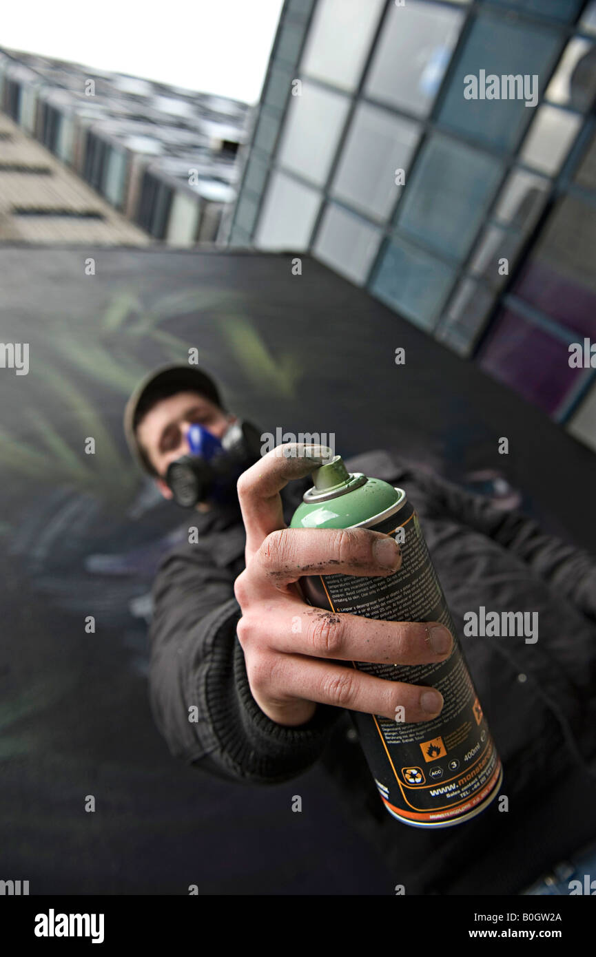 Graffiti Artist with mask spray paints a mural on a wall Stock Photo ...