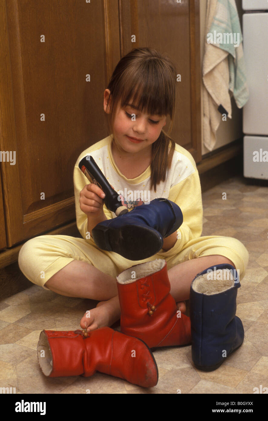 child, little girl sitting on floor cleaning shoes, doing chores Stock ...