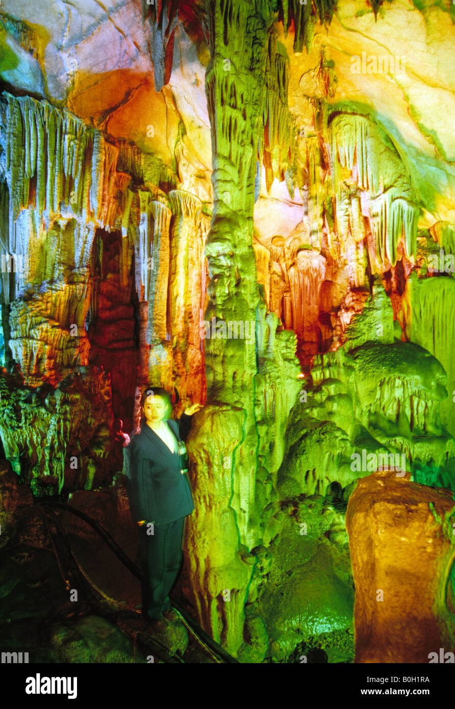 Garish colored lights on tour guide and limestone formations in Reed ...