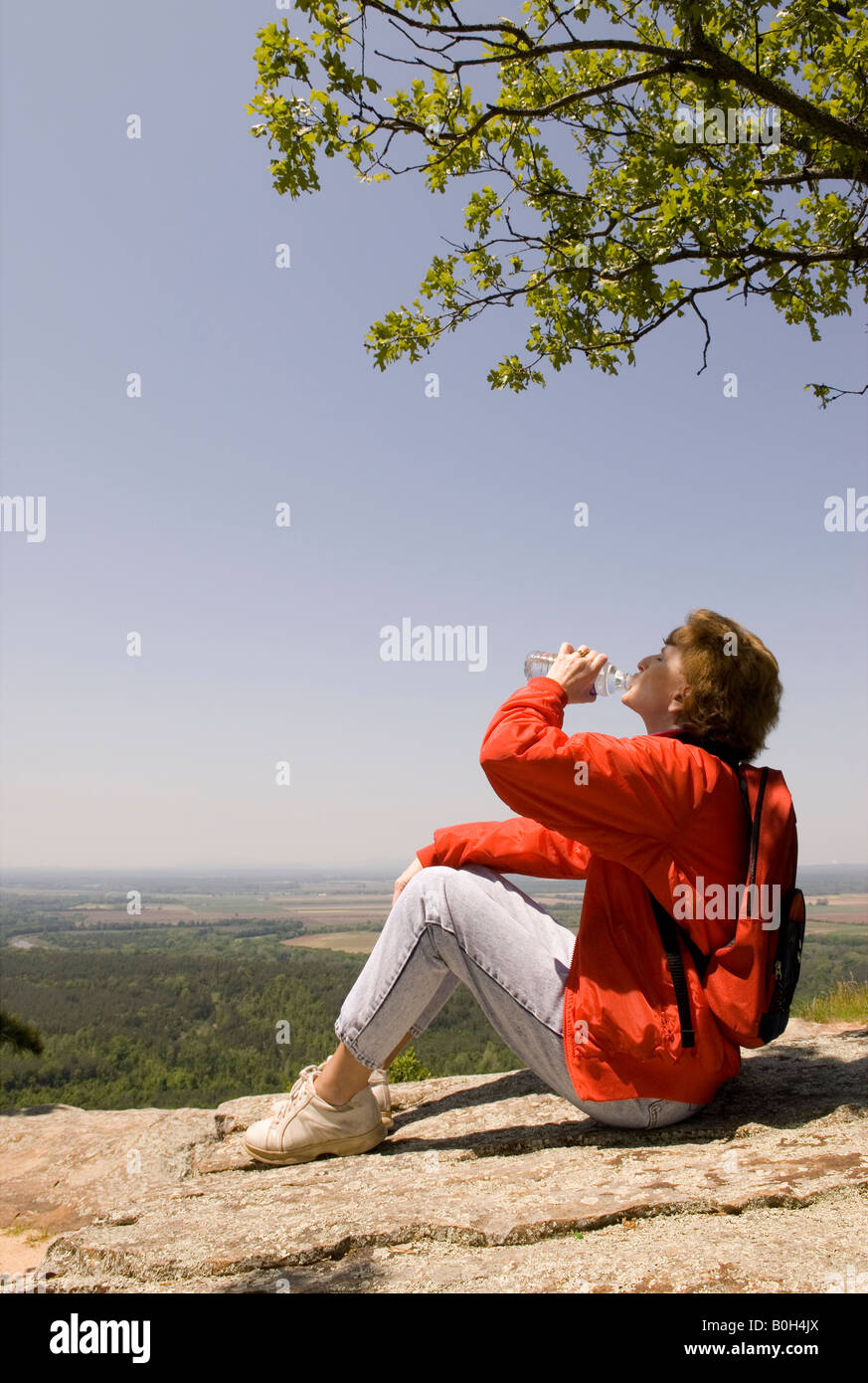 Caucasian woman in her early 50s takes a break and drinks bottled water ...