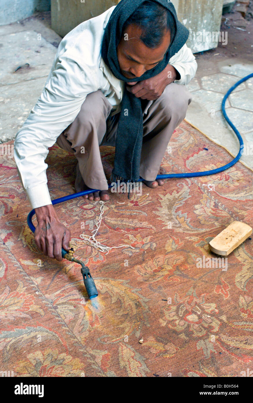 INDIA JAIPUR Indian craftsman using a blow torch to singe the back of a ...