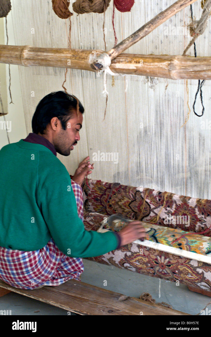 INDIA JAIPUR Young Indian craftsman consults a pattern as he works on a ...