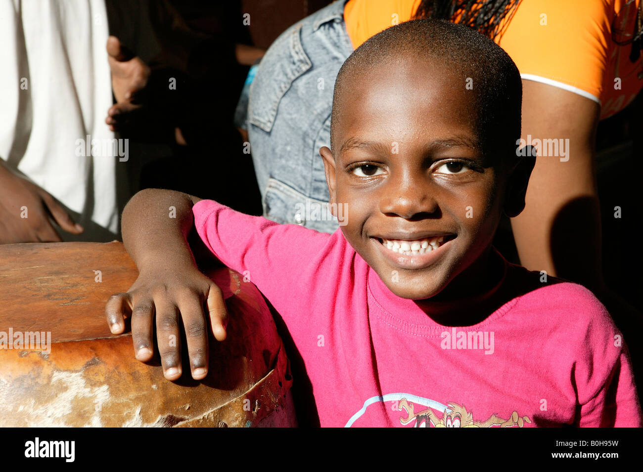 Smiling boy leaning on a traditional African drum at a wedding in ...