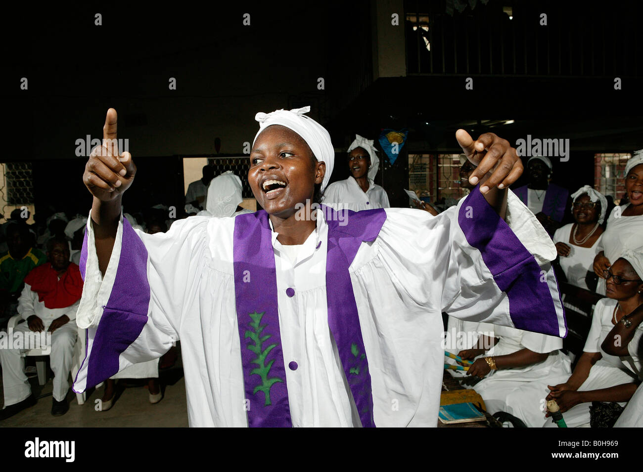 Woman dressed in white with purple sash conducting during a church ...