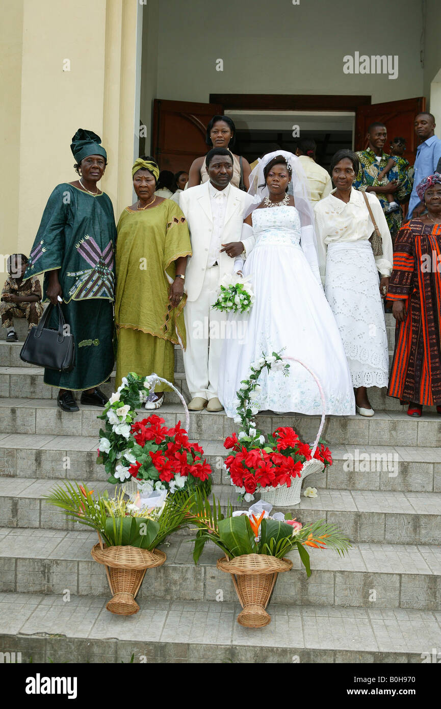 Bride, groom and guests standing behind flowers on steps for a group ...