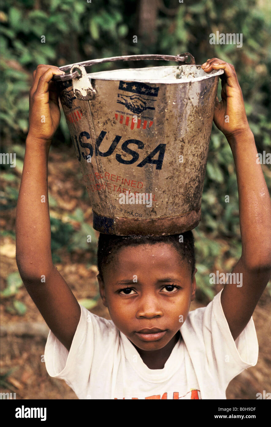 A child collecting water using a bucket of vegetable oil donated by ...