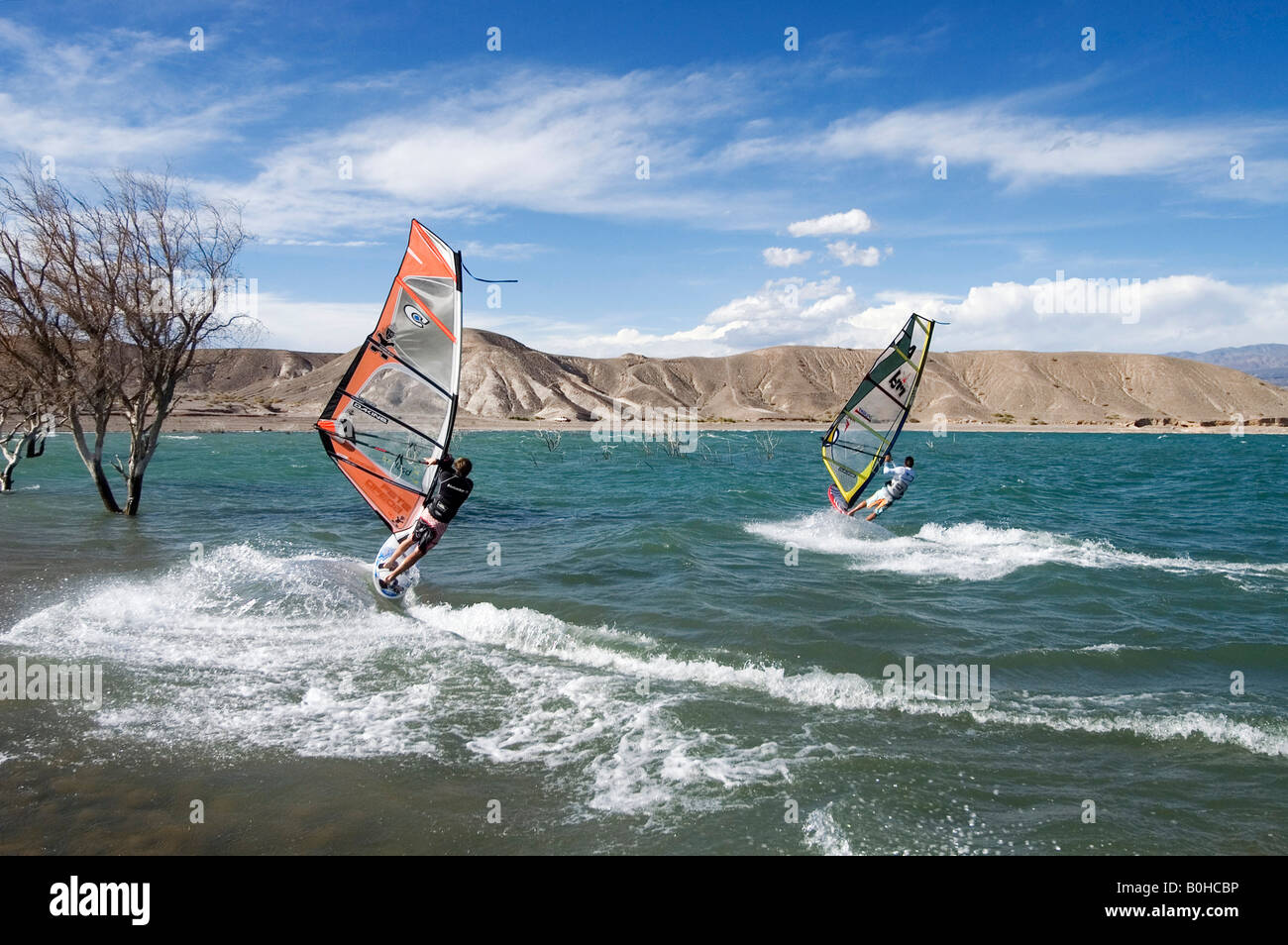 Two windsurfers sailing at high speed across the windswept dam at ...