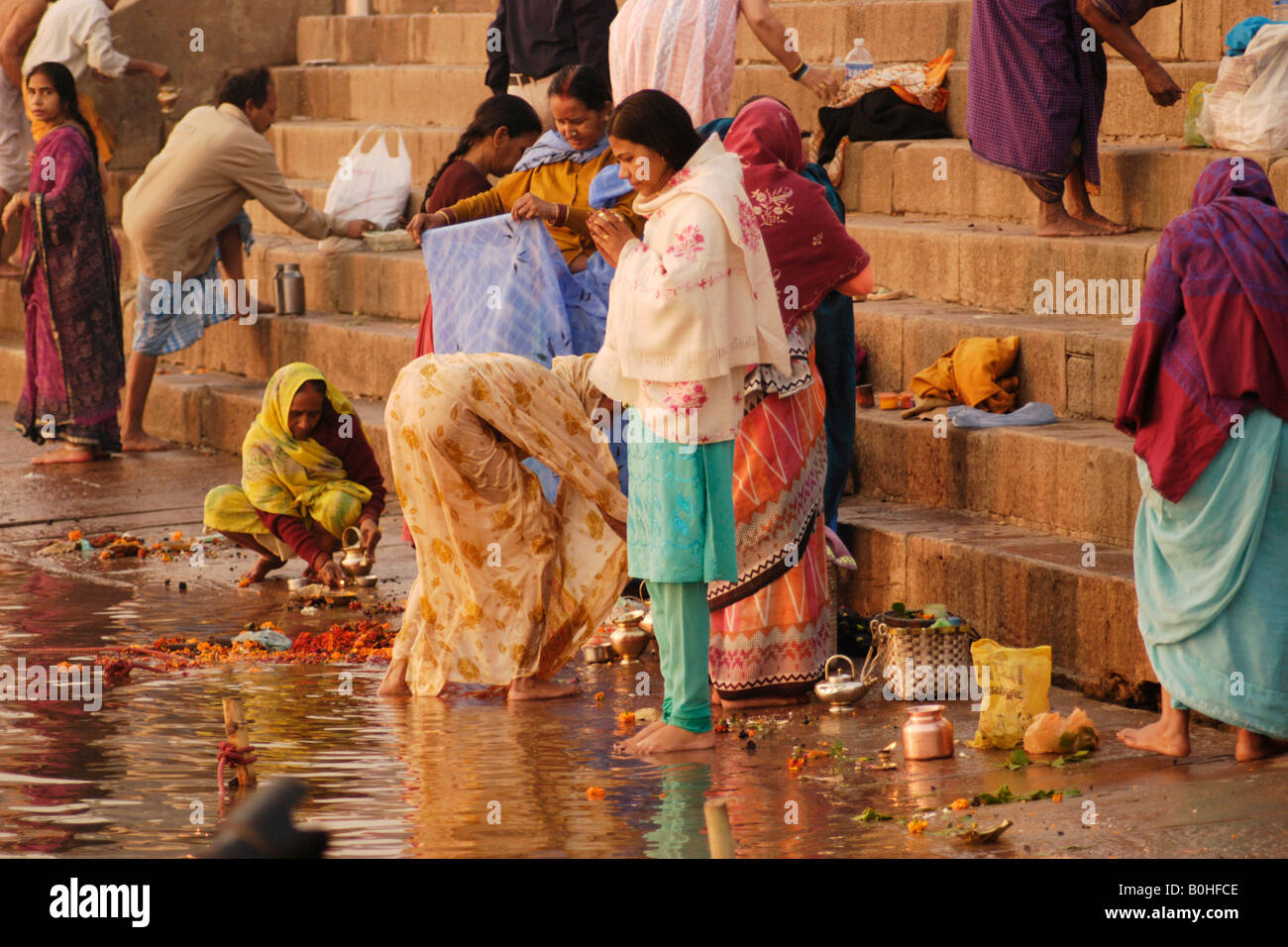 Hindu washing and praying in the morning sunrise on steps of Ghat ...