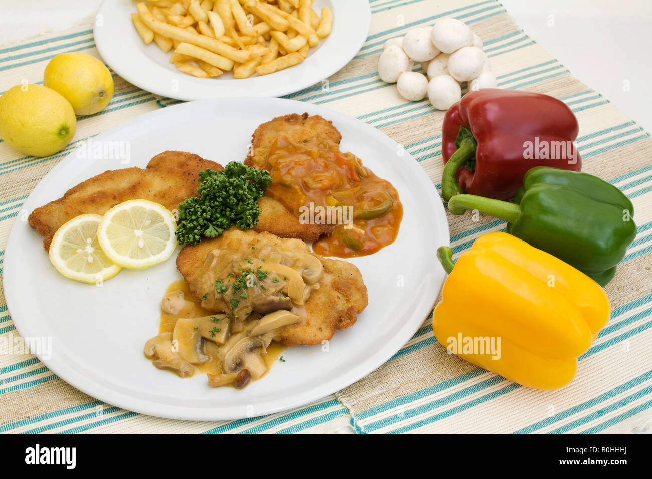 Wiener schnitzel served on a white plate surrounded by a green, red and ...