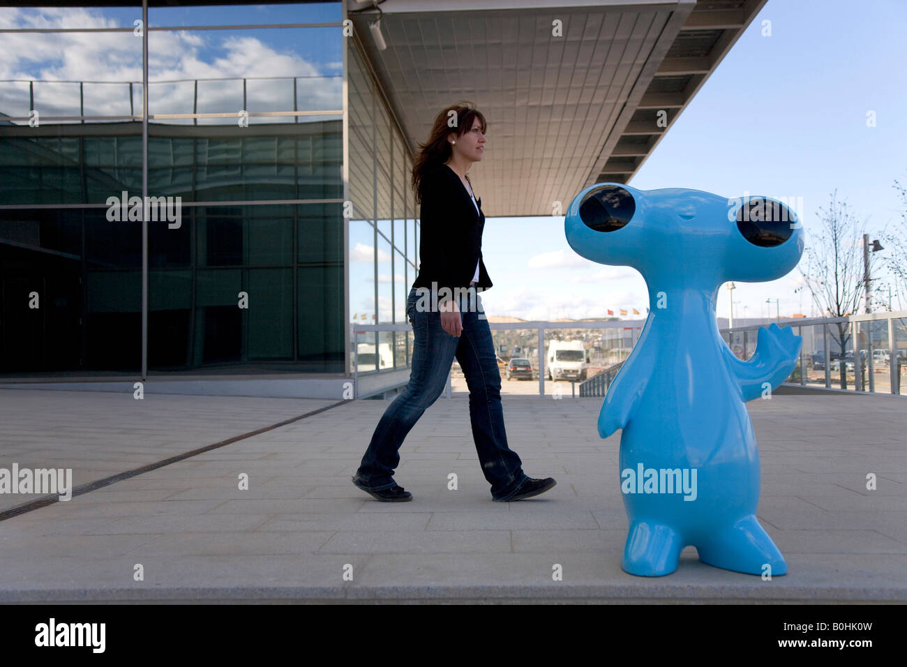 Woman walking past a blue statue of Fluvi, the Expo 2008 mascot ...