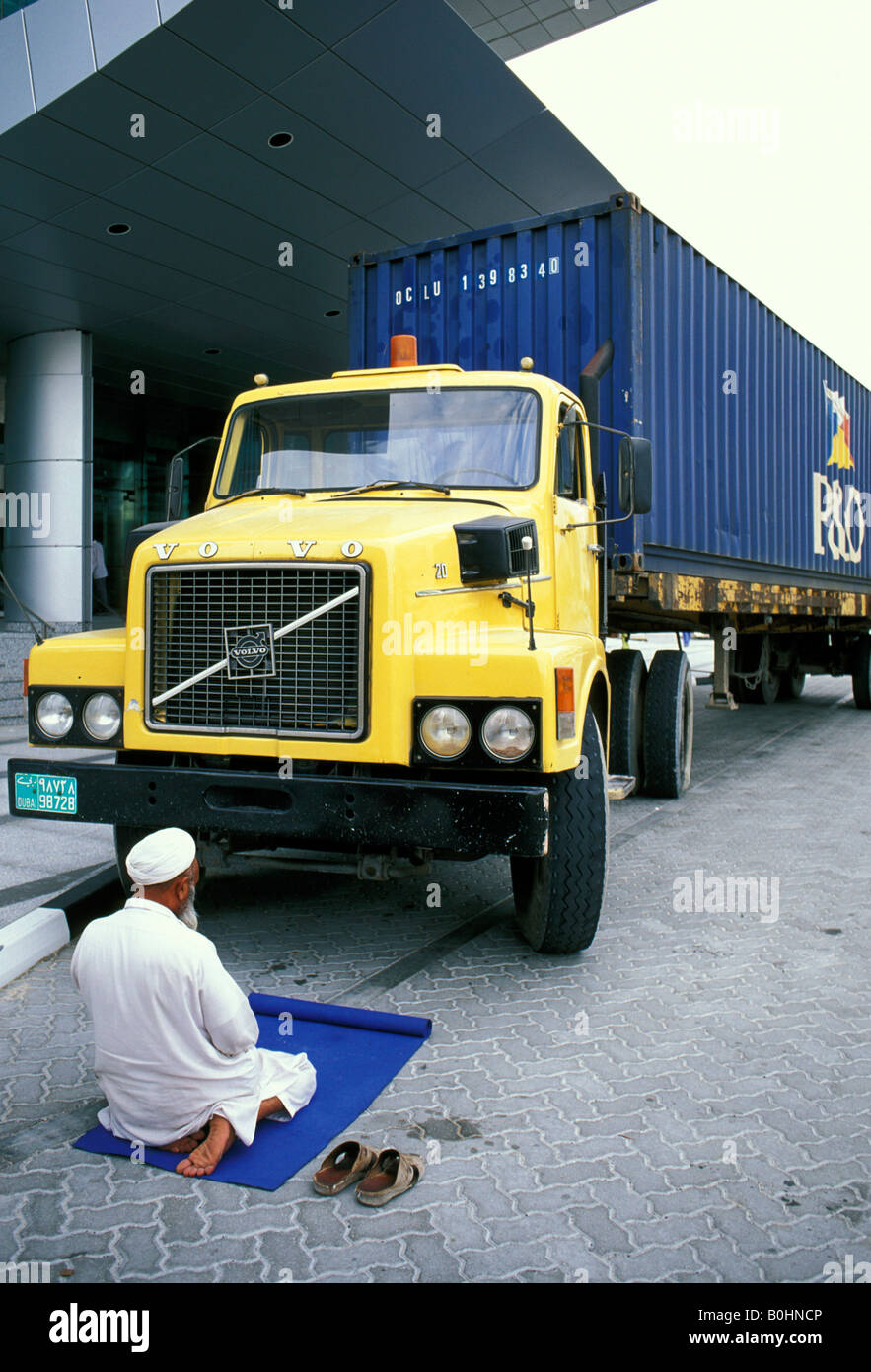 A Muslim driver kneeling to pray in front of his truck, United Arab ...